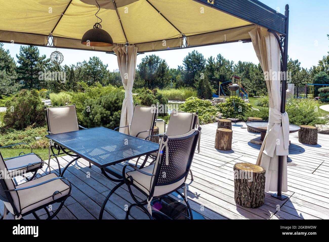 Patio with dining table and chairs under canopy and barbecue area in ...