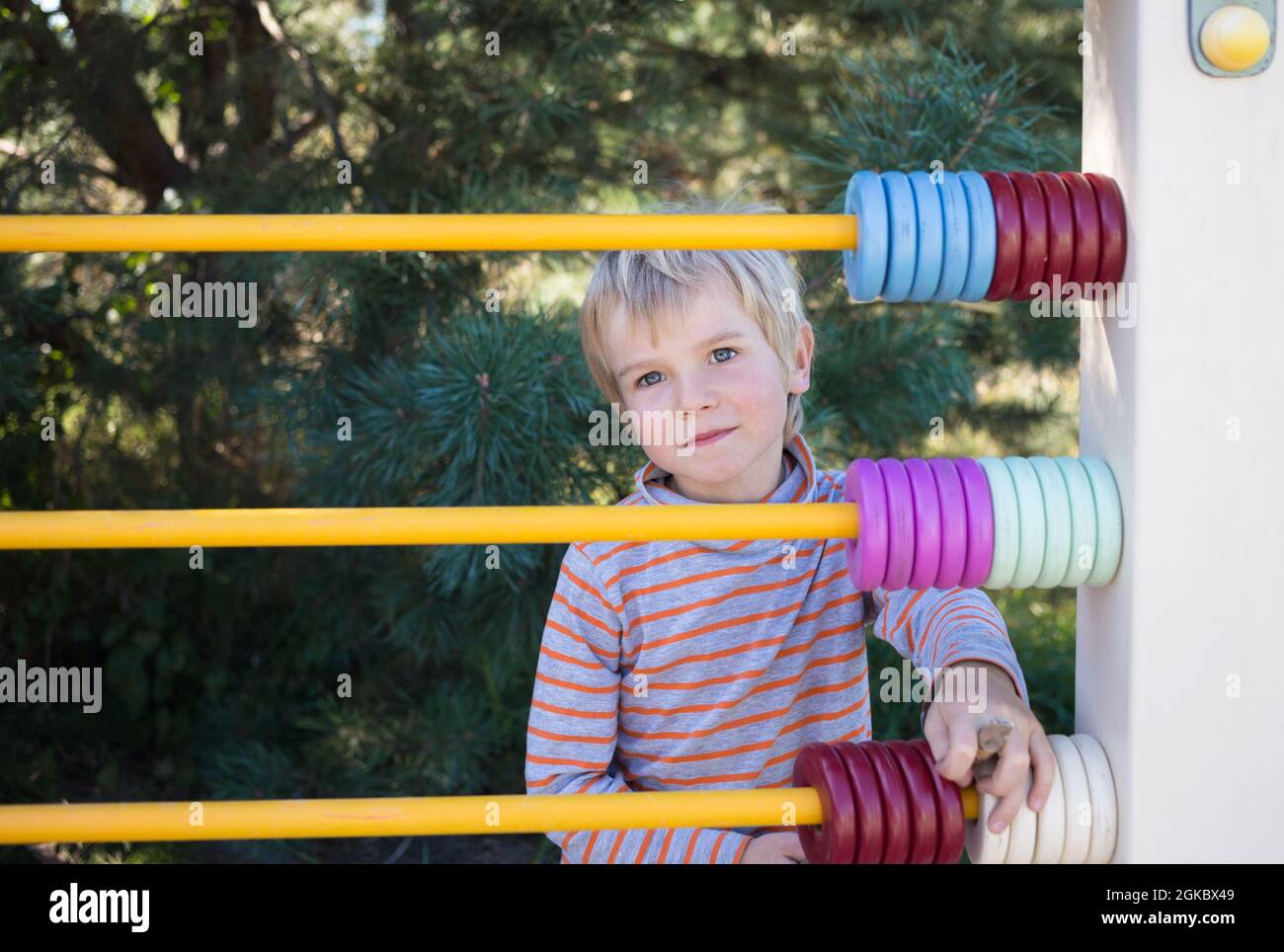 Little boy with wooden colorful abacus does math exercises, looks into ...