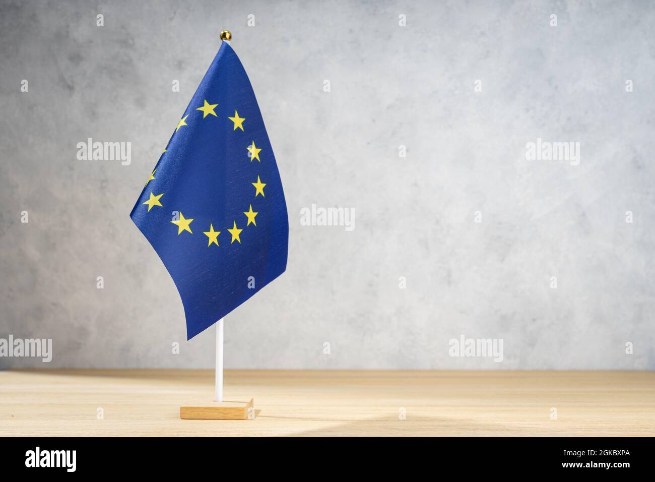 European Union table flag on white textured wall. Copy space for text ...