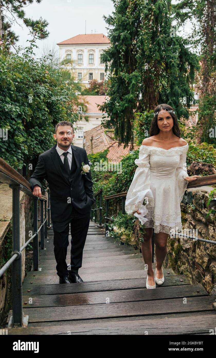 Bride and groom standing on wooden stairs in city on their wedding day ...