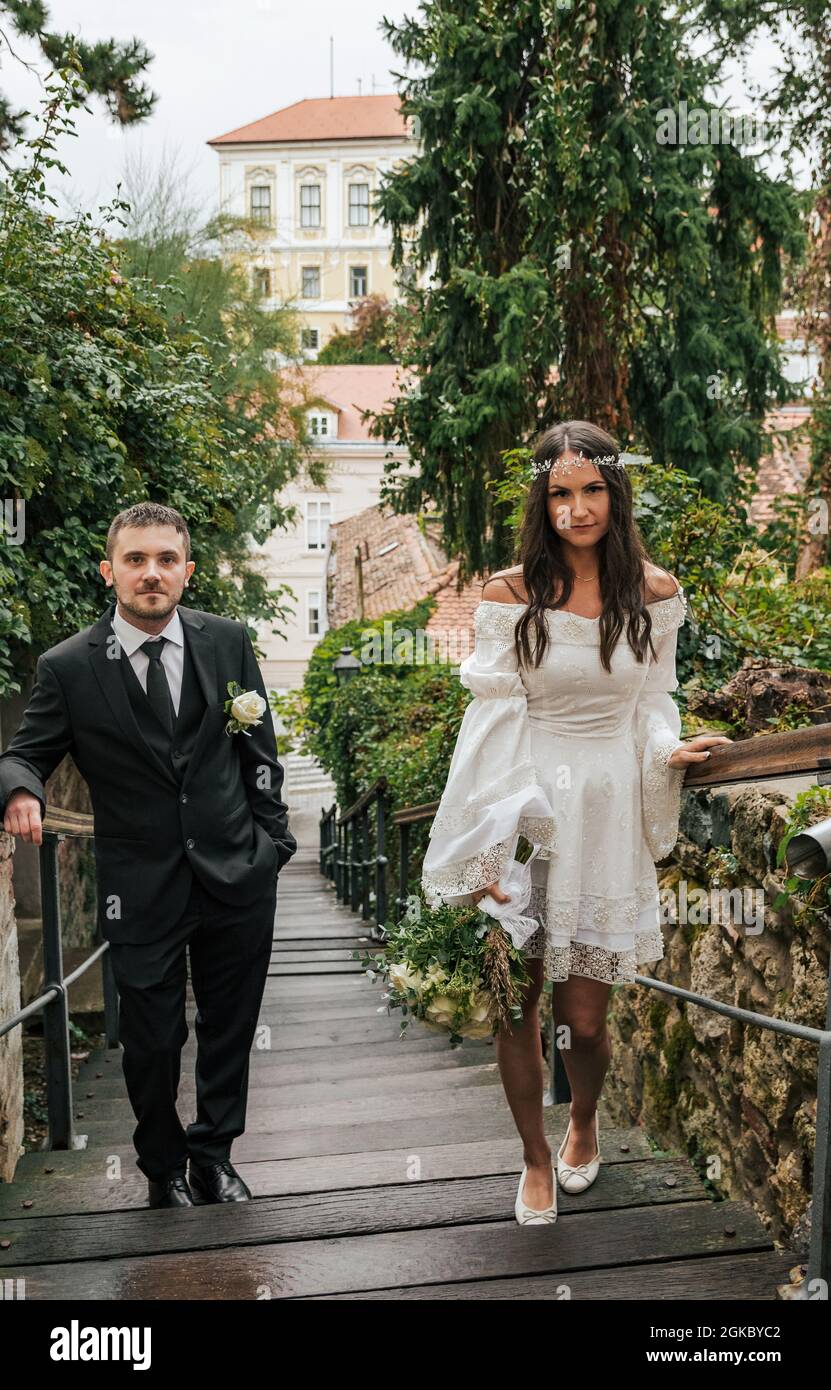 Bride and groom standing on wooden stairs in city on their wedding day ...