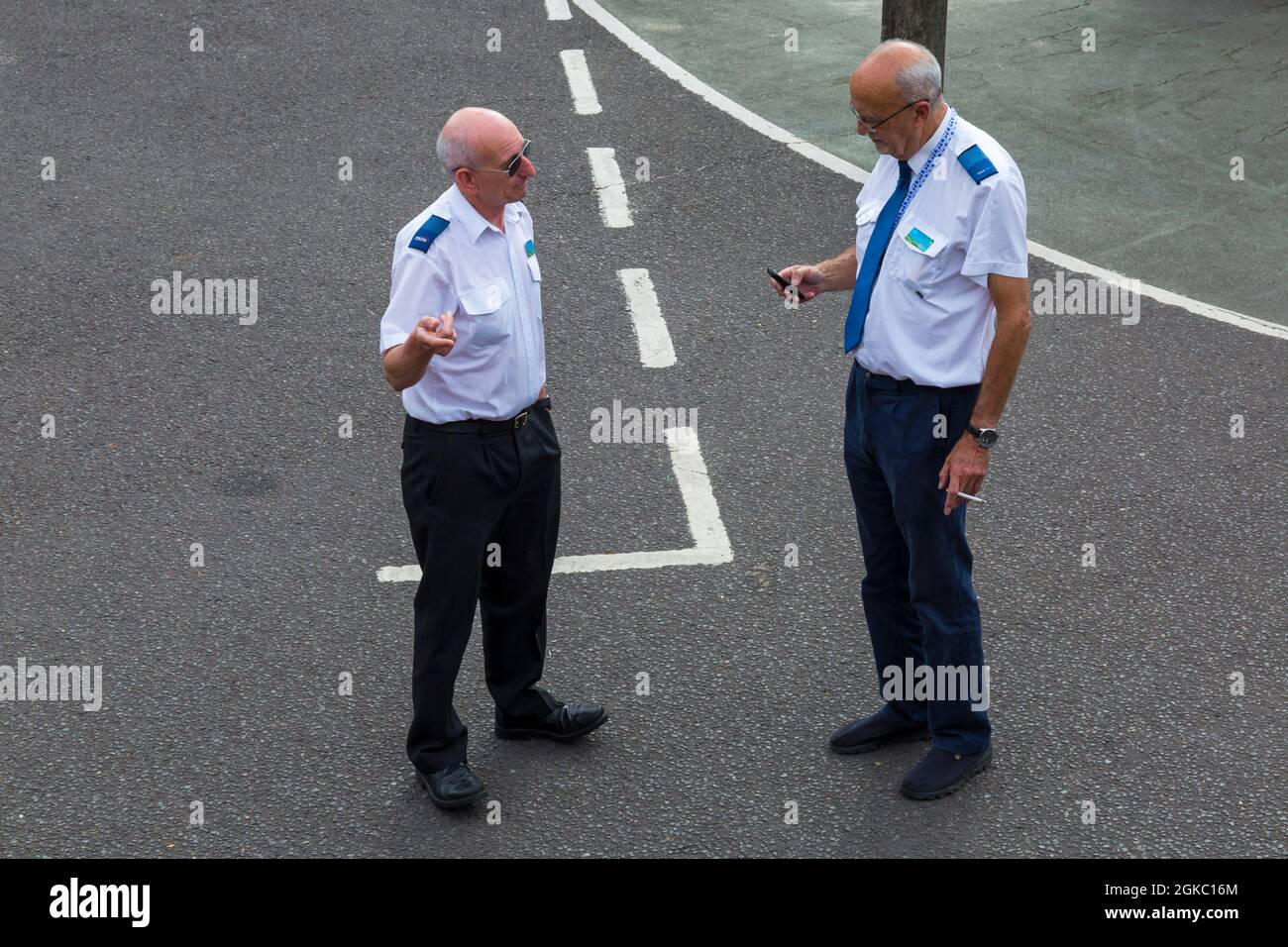 Two bus drivers standing chatting during their break in the New Forest ...