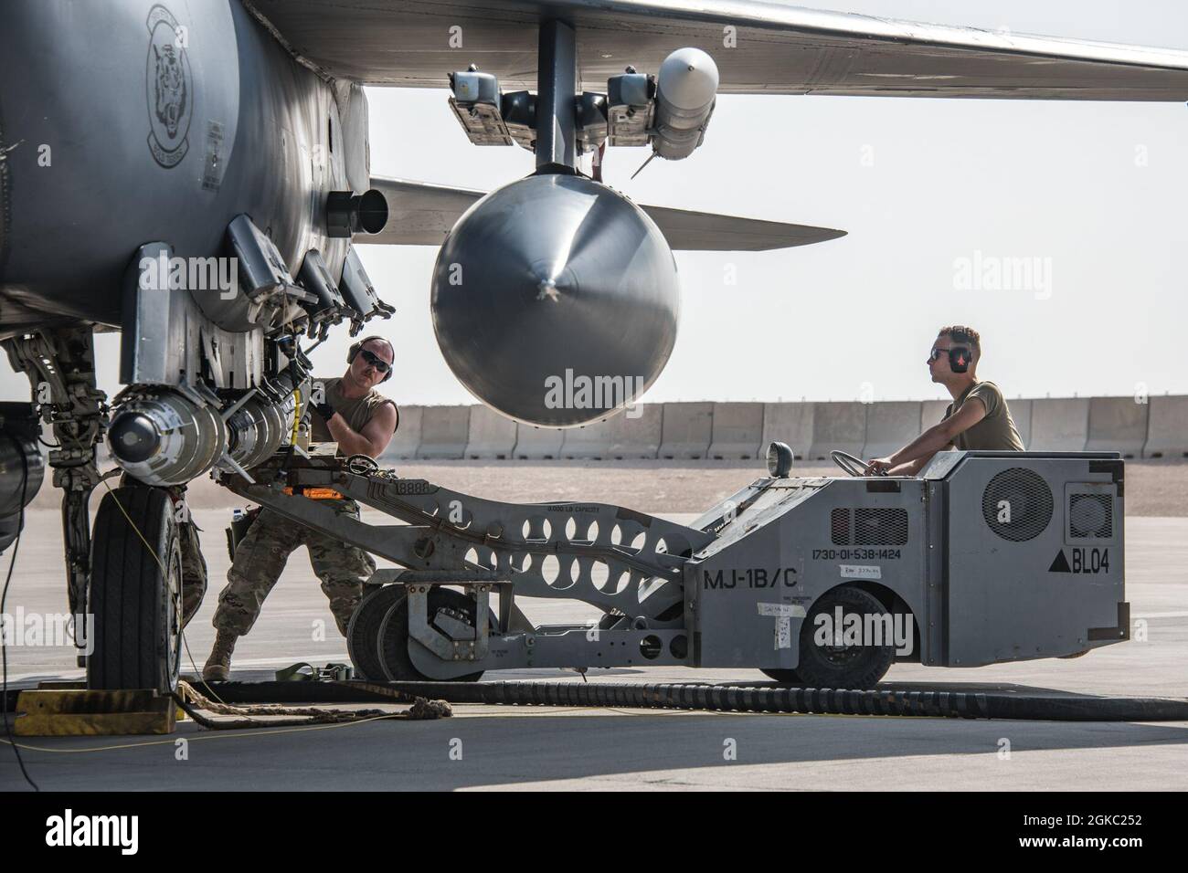 U.S. Airmen with the 379th Expeditionary Maintenance Squadron munitions flight load a GBU-38 ...