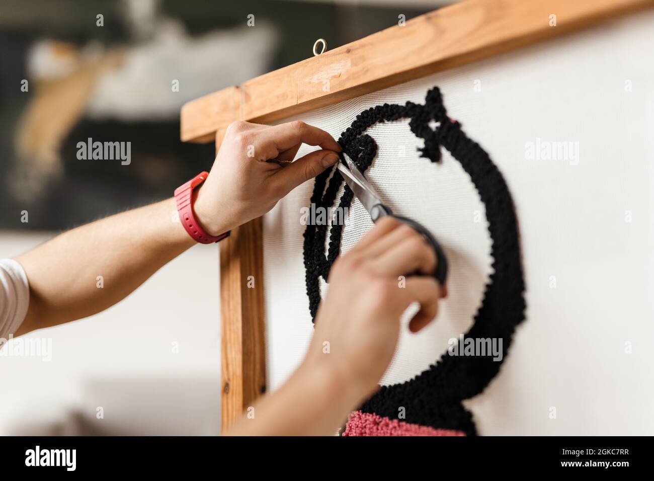 White man using scissors while working on craft rug indoors Stock Photo ...