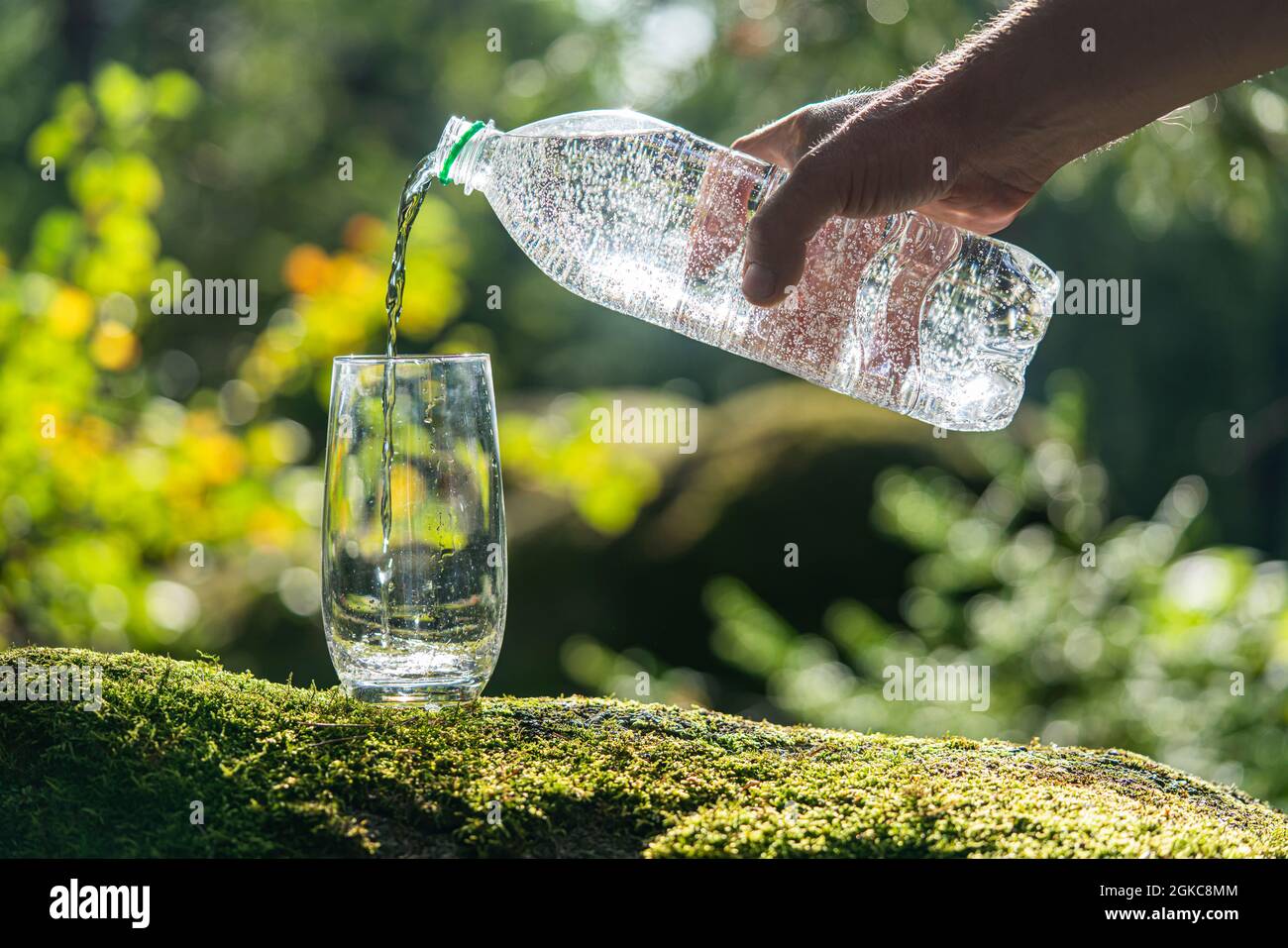 pouring water from a plastic bottle into a clear, clean glass with pure ...