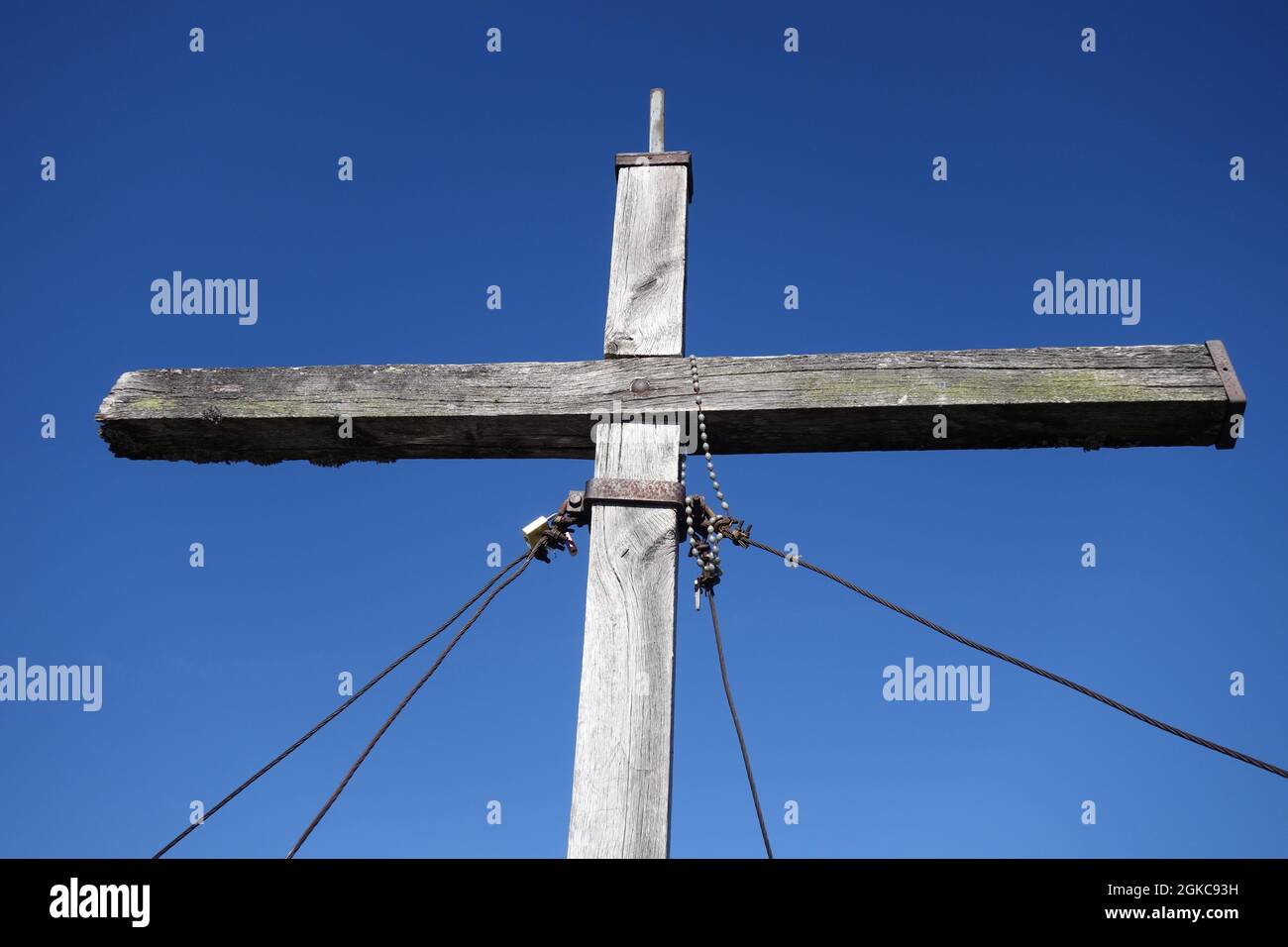 Low-angle shot of a wooden cross with electrical wires on a clear blue ...