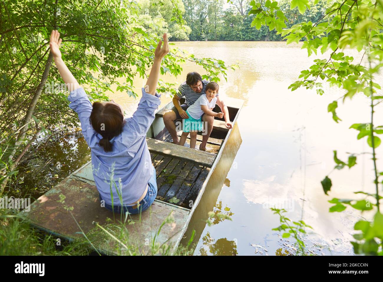 Family with child makes a trip in a boat on the lake in summer vacation ...
