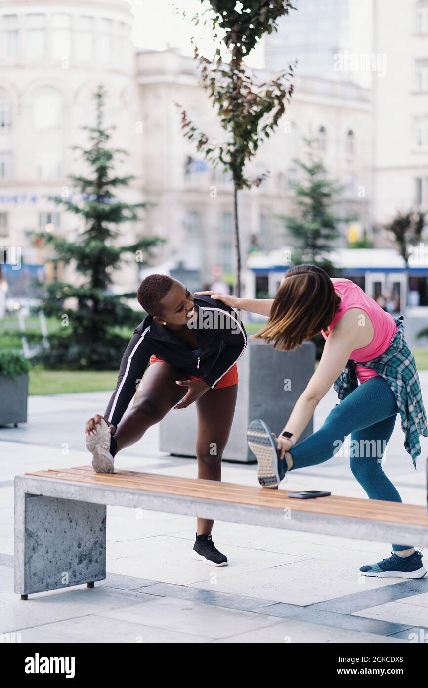 Two fit diverse young woman working out together in city square doing ...