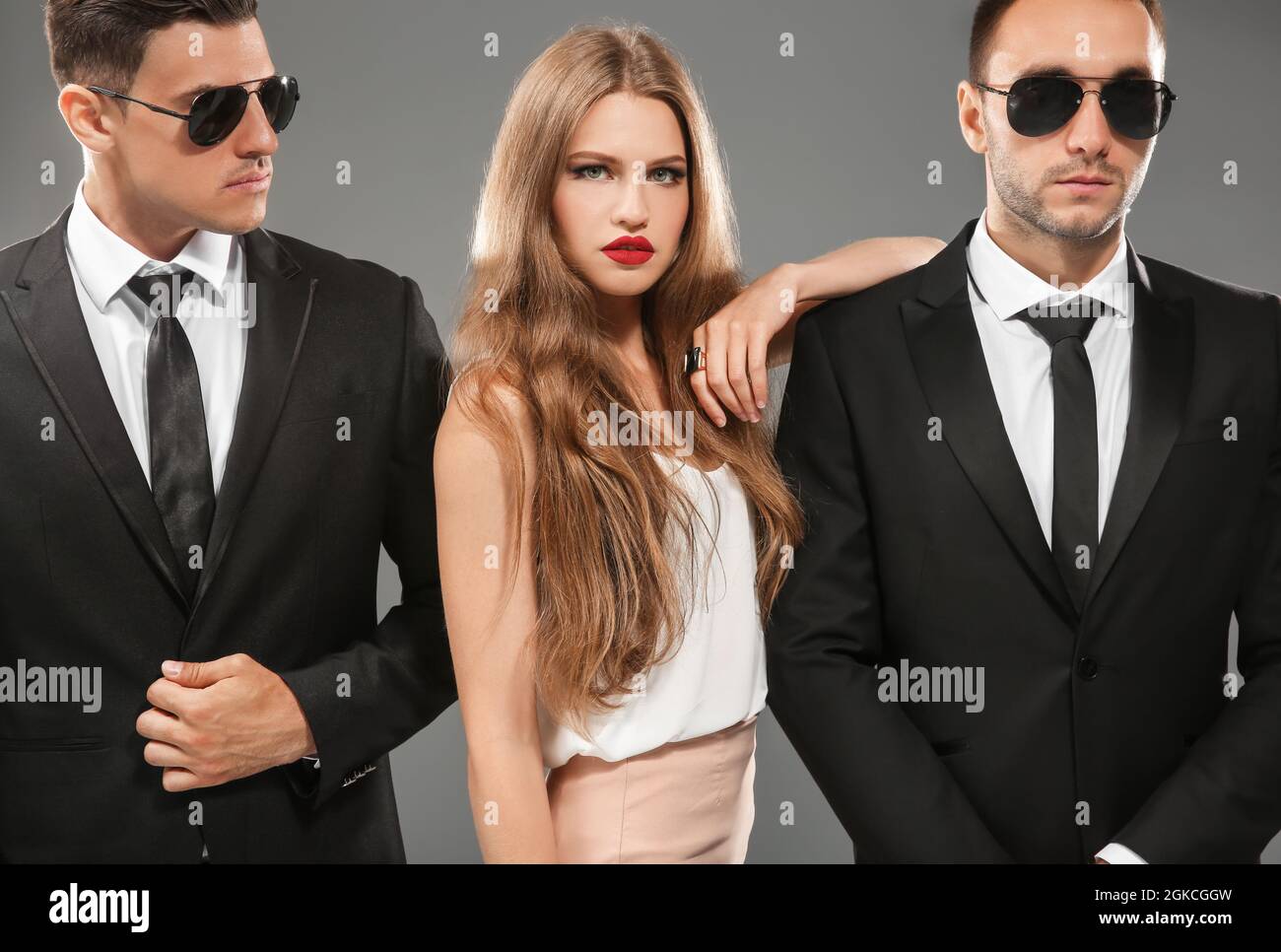 Famous celebrity with bodyguards on grey background Stock Photo - Alamy