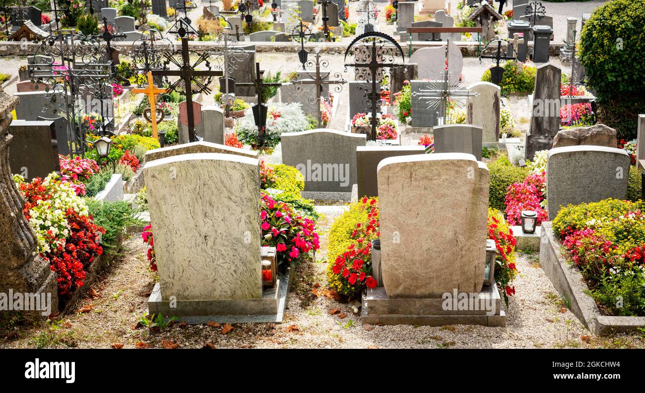 Peaceful Tombstone and graves in an ancient church graveyard. Beautiful flowers and trees in ...