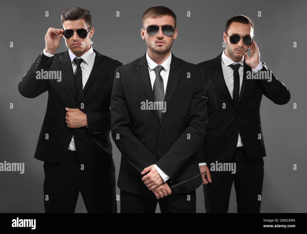 Handsome bodyguards on grey background Stock Photo - Alamy