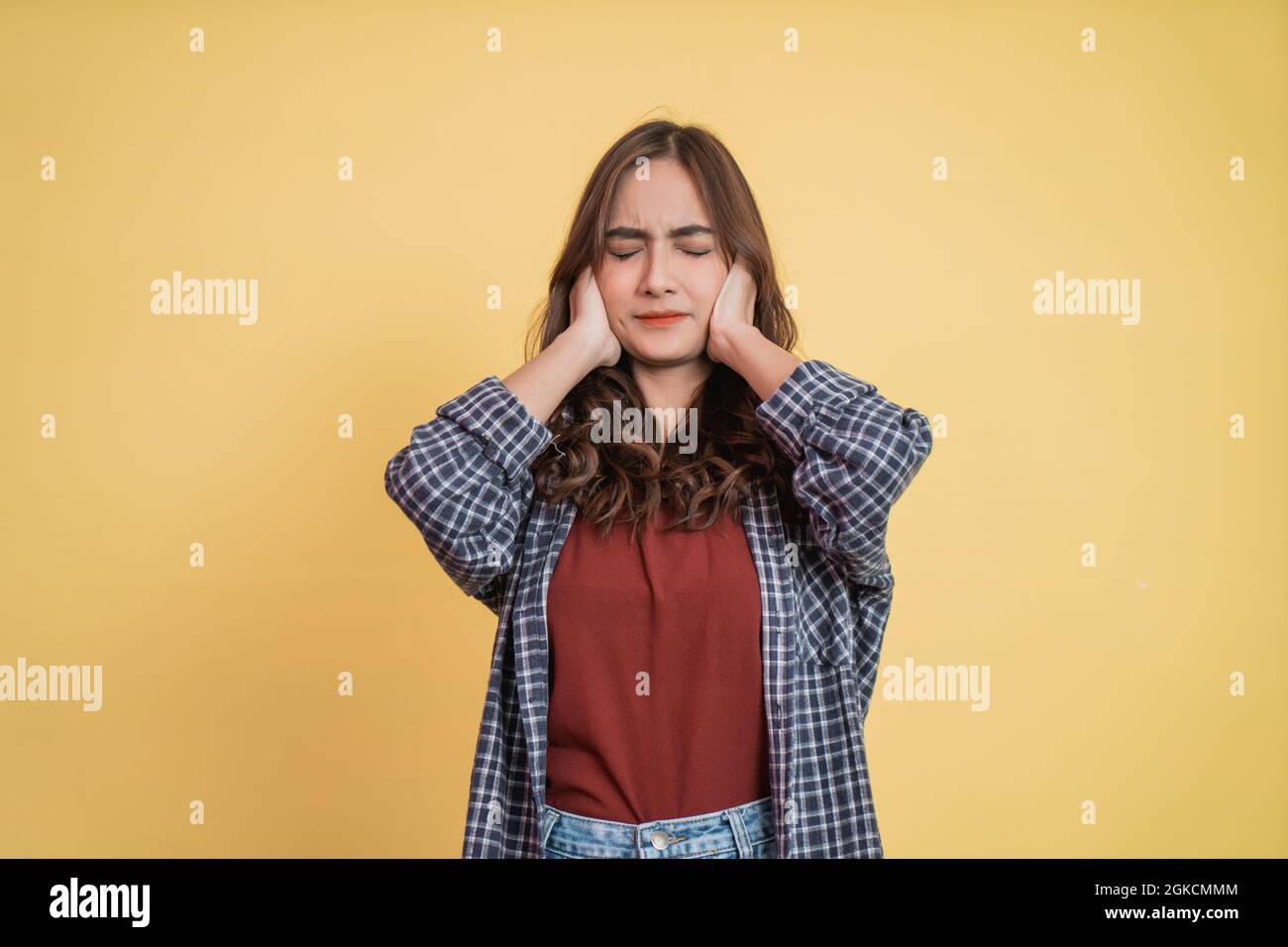 a beautiful girl covers her ears with both hands and closes her eyes ...