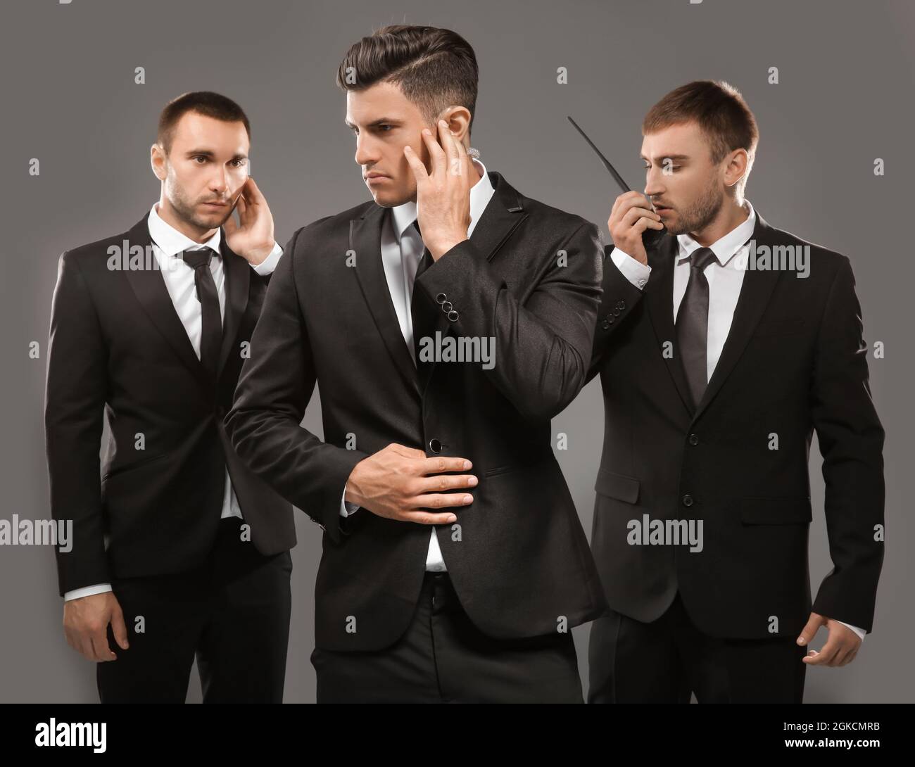 Handsome bodyguards on grey background Stock Photo - Alamy