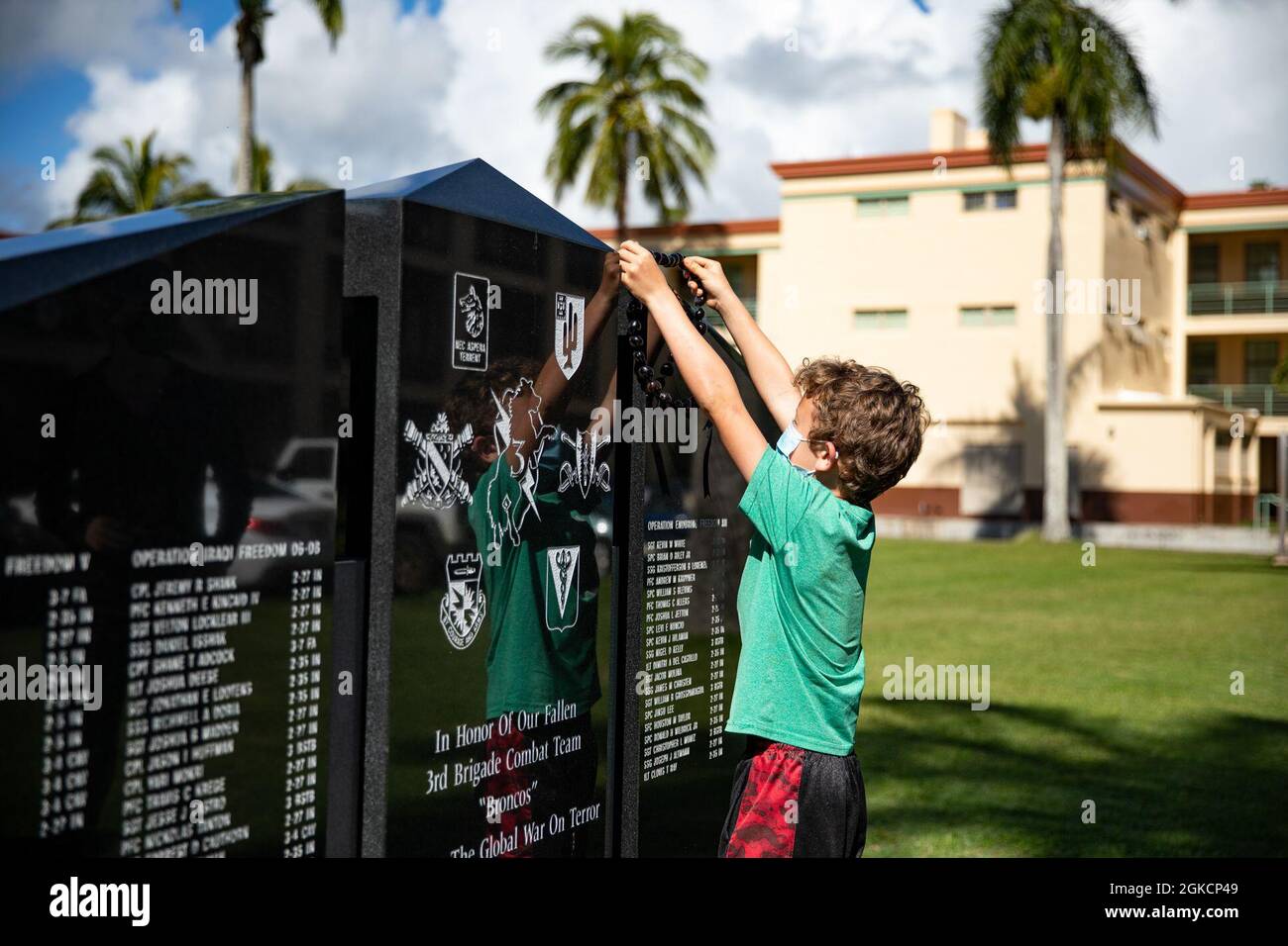 A son of Ed Ray, a Gold Star Family Member, puts a lei on the memorial ...