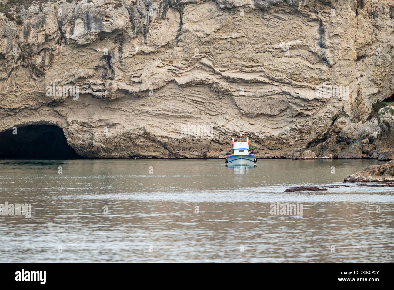 Small fishing boat sailing between reefs and with a large background of ...