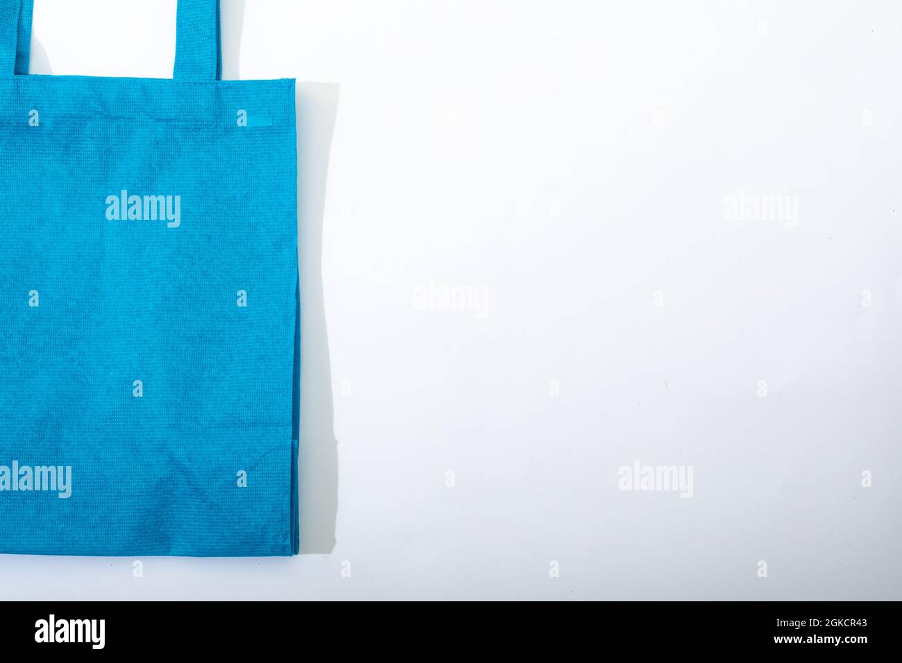 Composition of empty blue canvas shopping bag lying flat on white ...