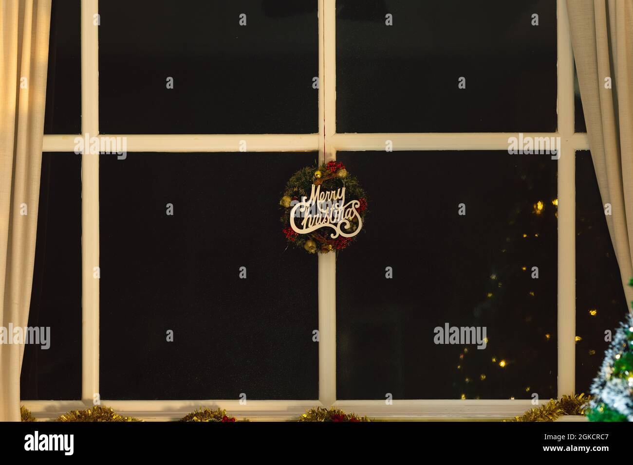 Composition of merry christmas sign with decorations hanging in window ...