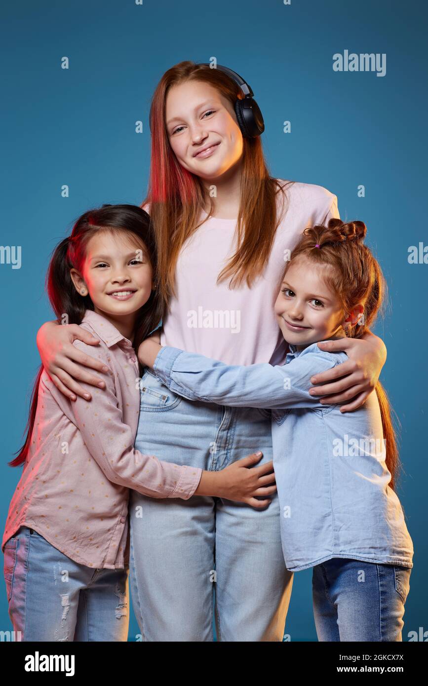 three kids girls standing together on blue background Stock Photo - Alamy