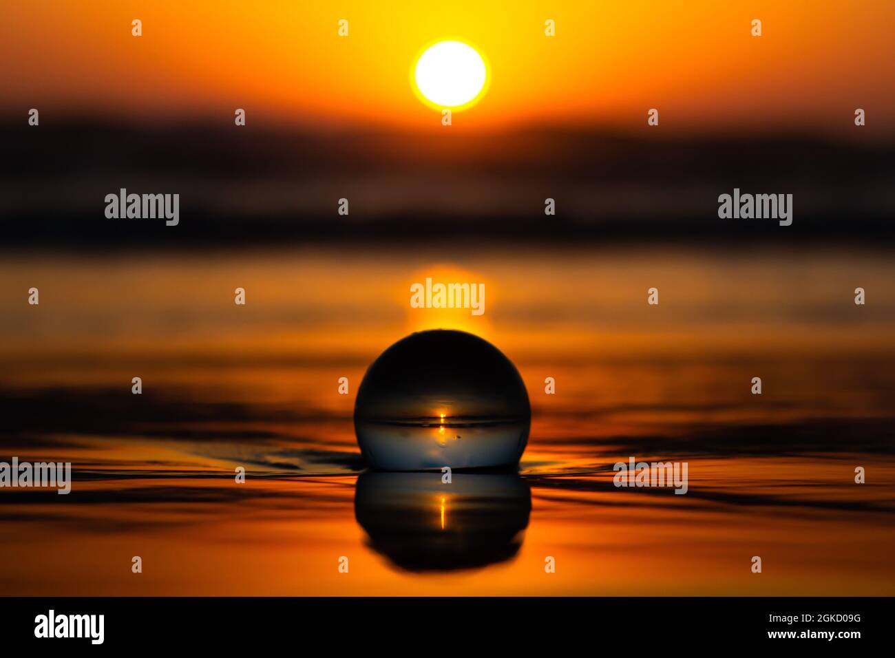 Double sunset with crystal ball on a beach Stock Photo - Alamy