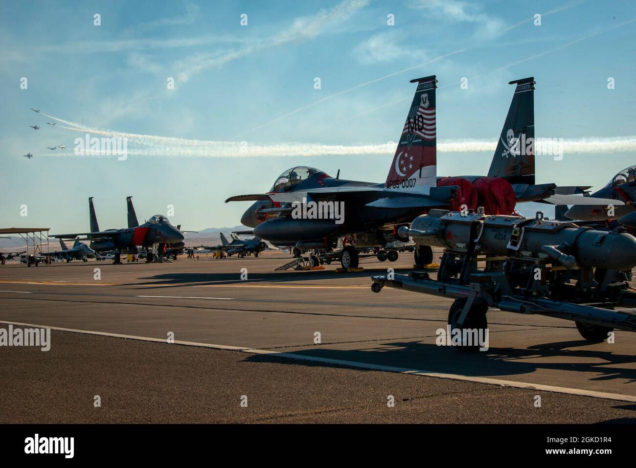 The U.S. Thunderbirds fly in the background of F-15SG Strike Eagles ...