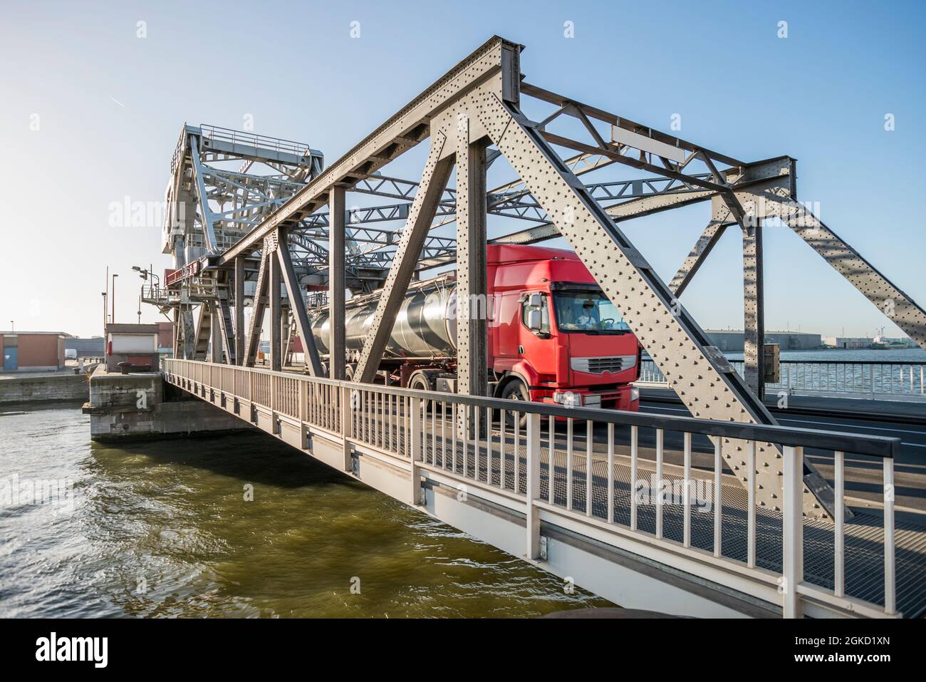Red tanker truck crossing a lifting metal bridge with many rivets ...