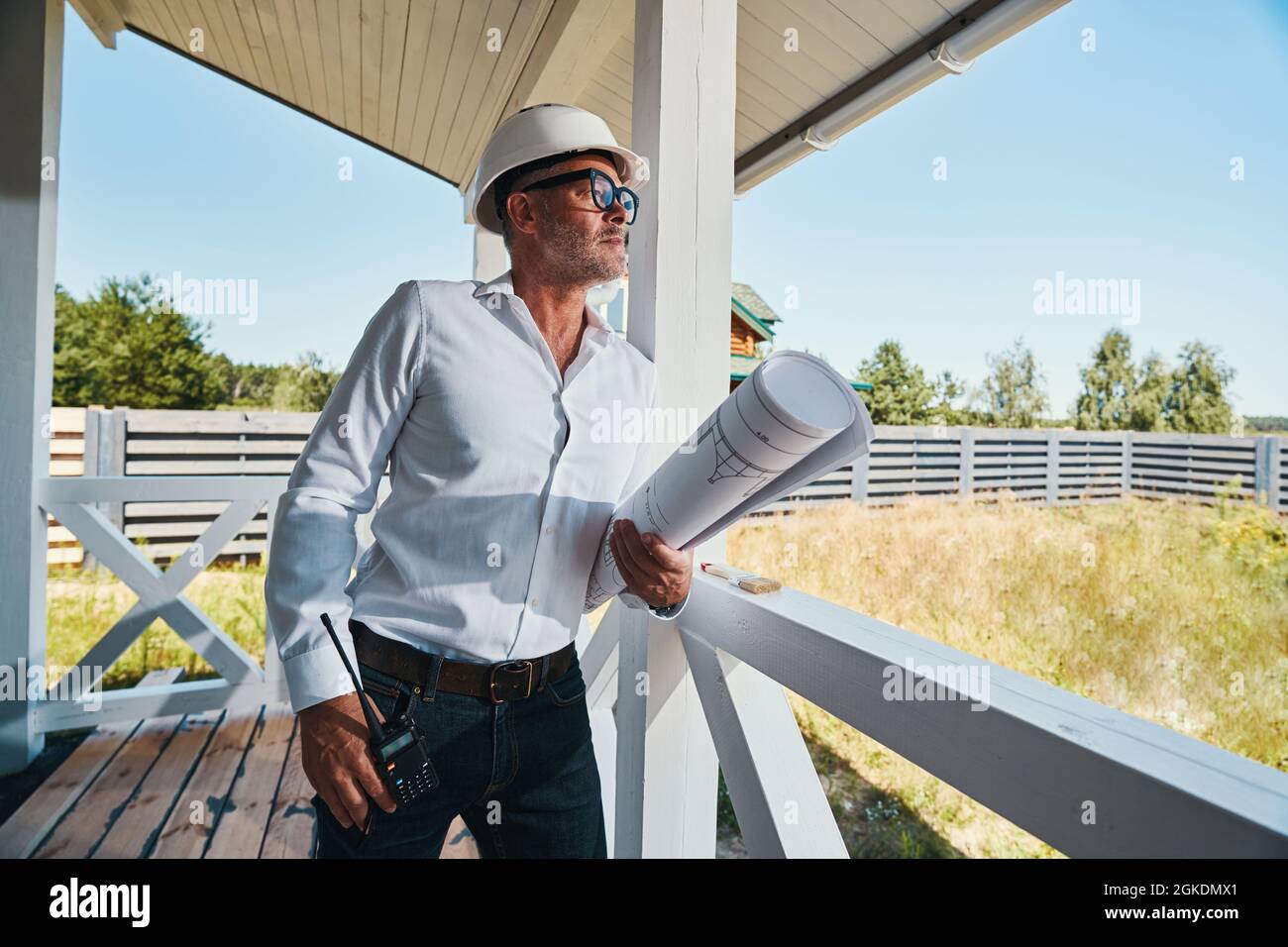 Housebuilder with drawings in arms leaning on porch railings Stock ...