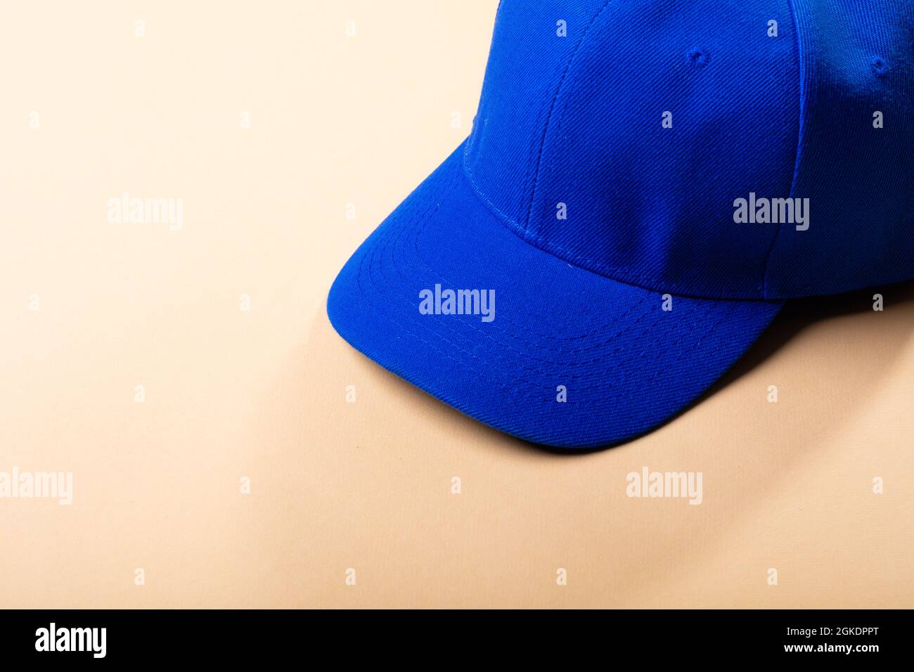 Composition of traditional peaked blue baseball cap on pale brown ...