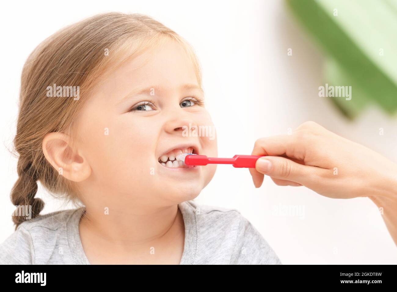 Mother brushing daughter's teeth on blurred background Stock Photo - Alamy