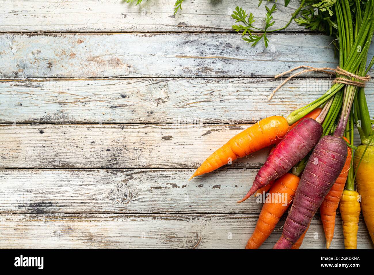 Colorful Rainbow carrot with their green leaves on wooden background ...