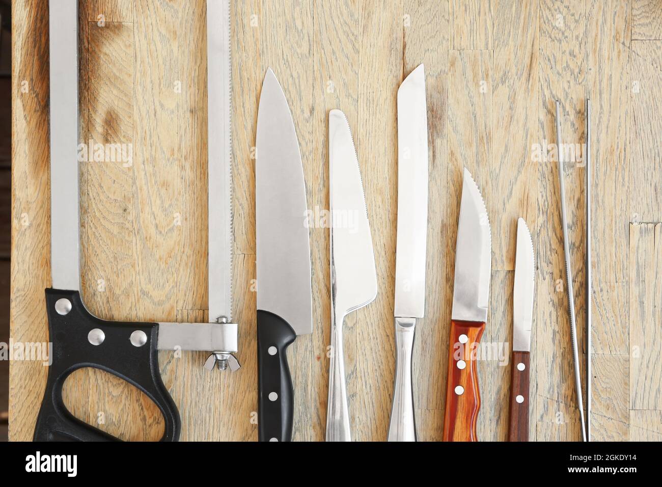 Set of sharp metal tools on wooden background Stock Photo - Alamy