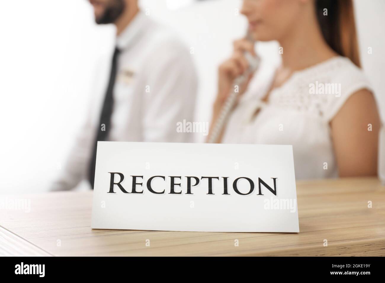 Reception sign and two busy hotel workers on background Stock Photo - Alamy