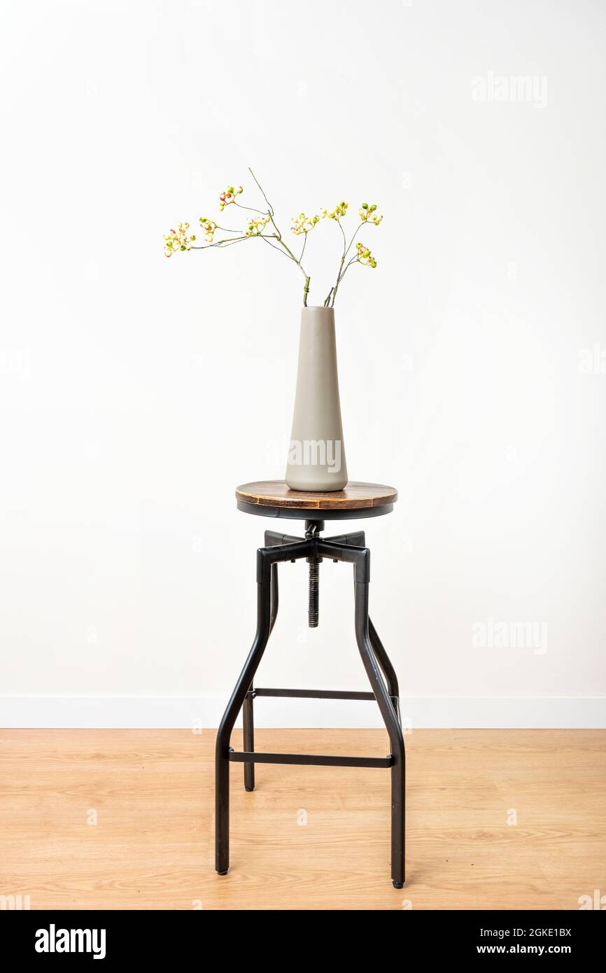 Gray vase with decorative branch of unripe blueberries on industrial ...