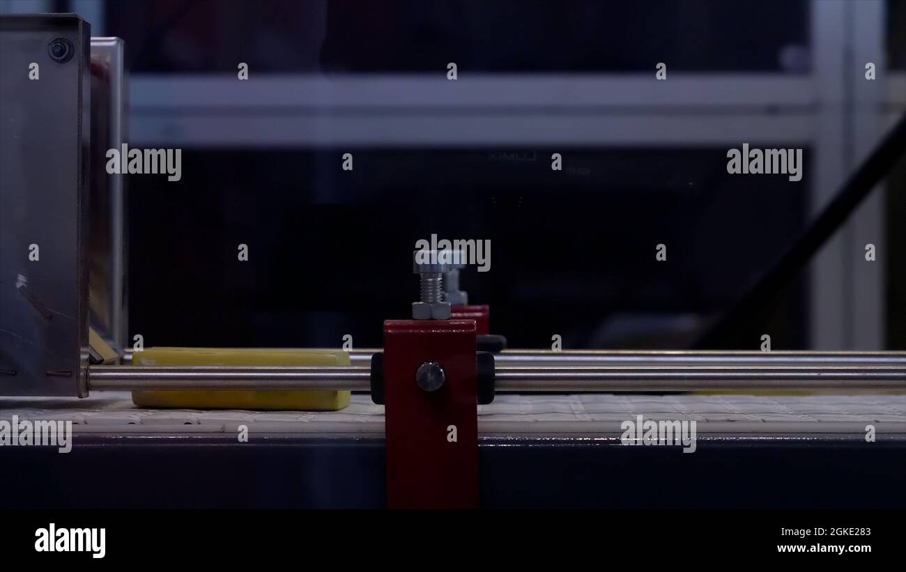 Close up side view of a modern conveyor line with moving yellow bricks ...