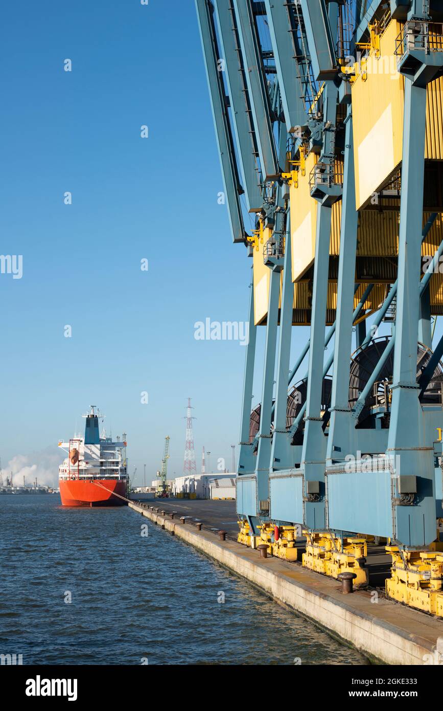 Ship, shipping cranes, seawater channel, refinery in the background and ...
