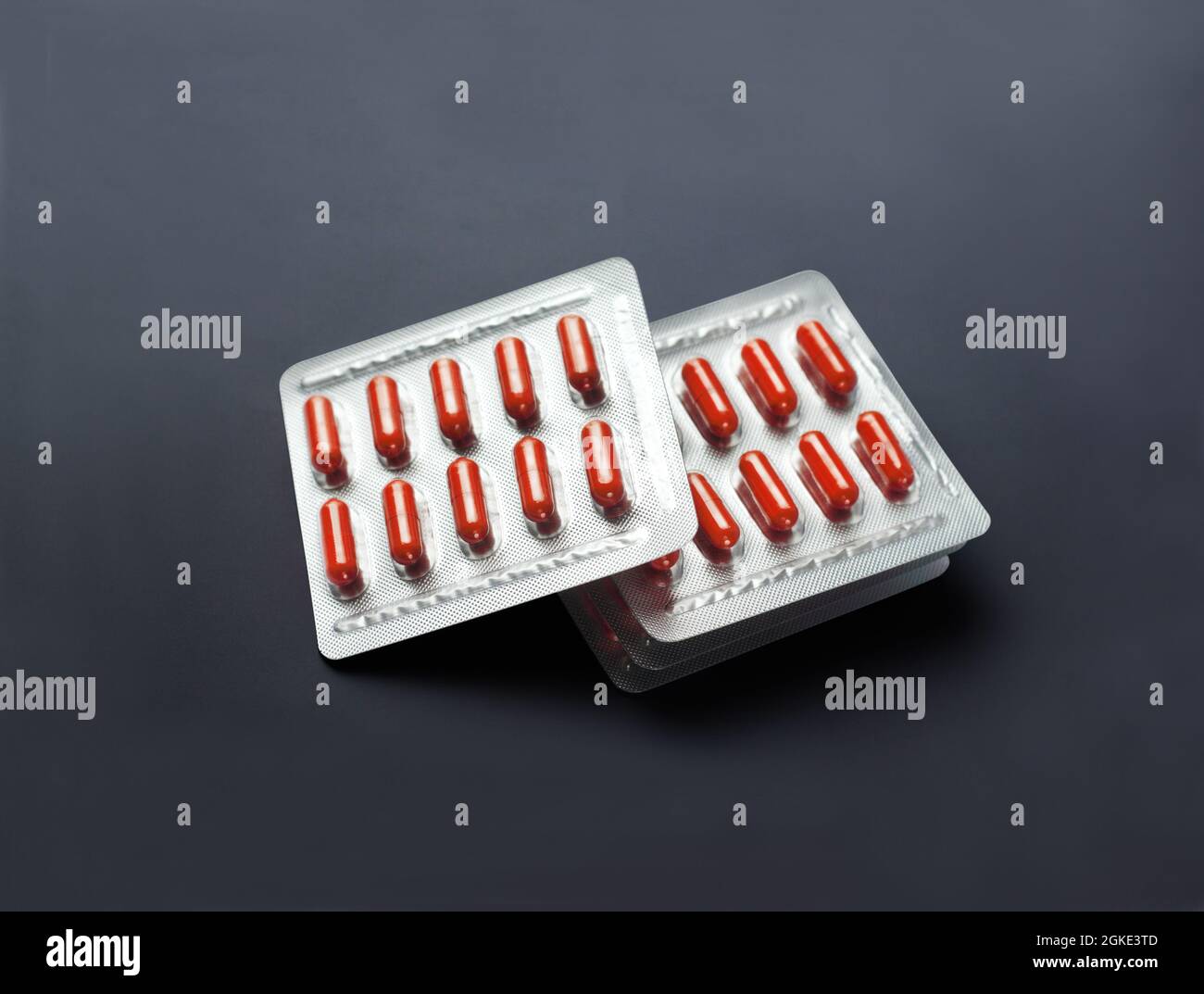 Red pill capsules in blister packs on gray background with copy space ...