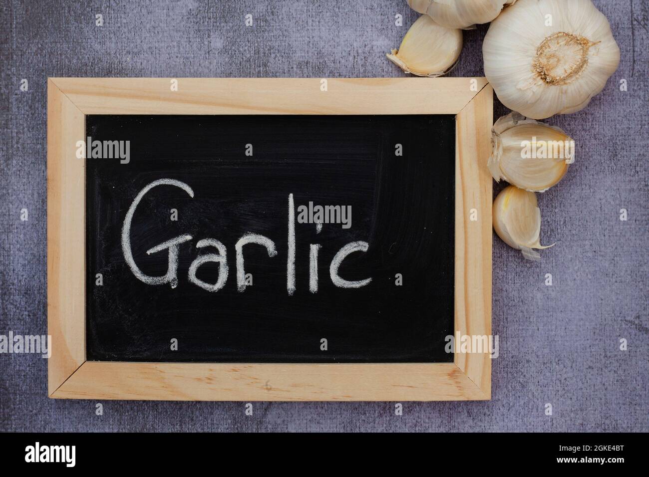 the word Garlic written on a black chalk board with garlic cloves and ...