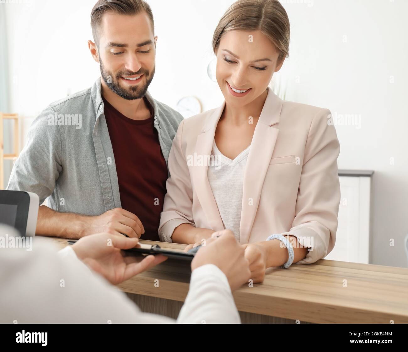Female receptionist and young couple in hotel Stock Photo - Alamy