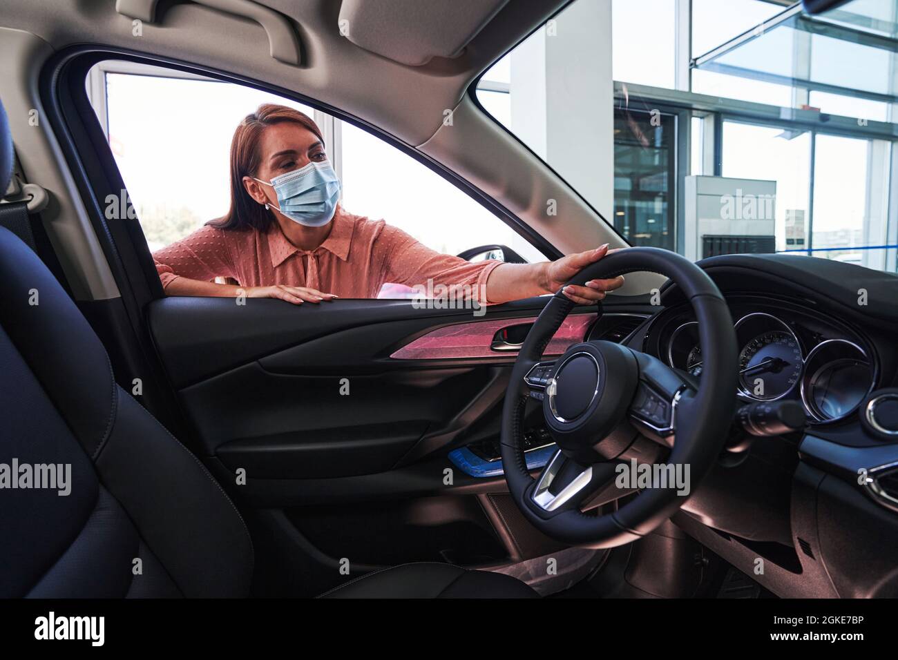 Curious female customer looking at the car salon Stock Photo - Alamy