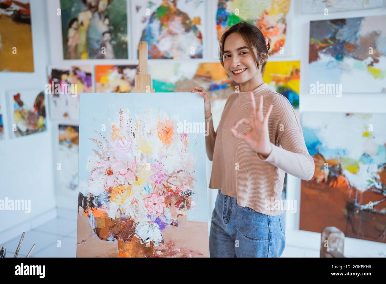 female artist standing next to her painting and showing thumb up Stock ...