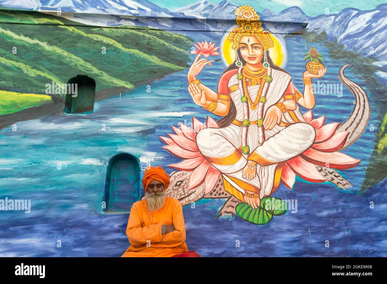 Sadhu in saffron robes in front of an image of a deity, For editorial ...