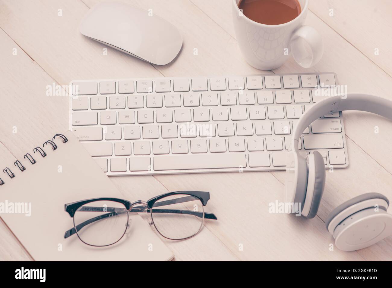 Notepad and computer keyboard on white table with headphone, eyeglasses ...