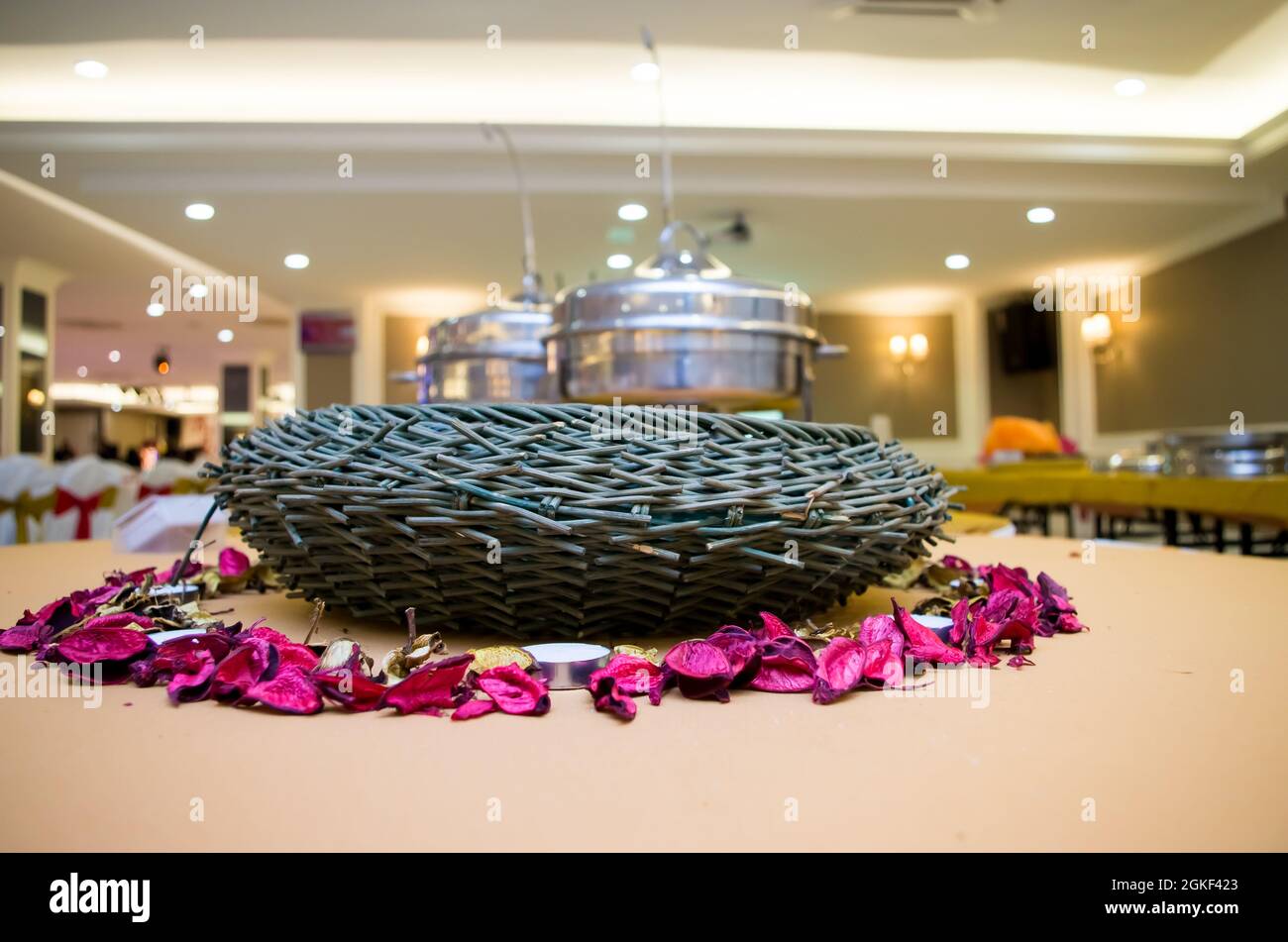 Thatch basket surrounded by pink rose leaves at a wedding ceremony ...