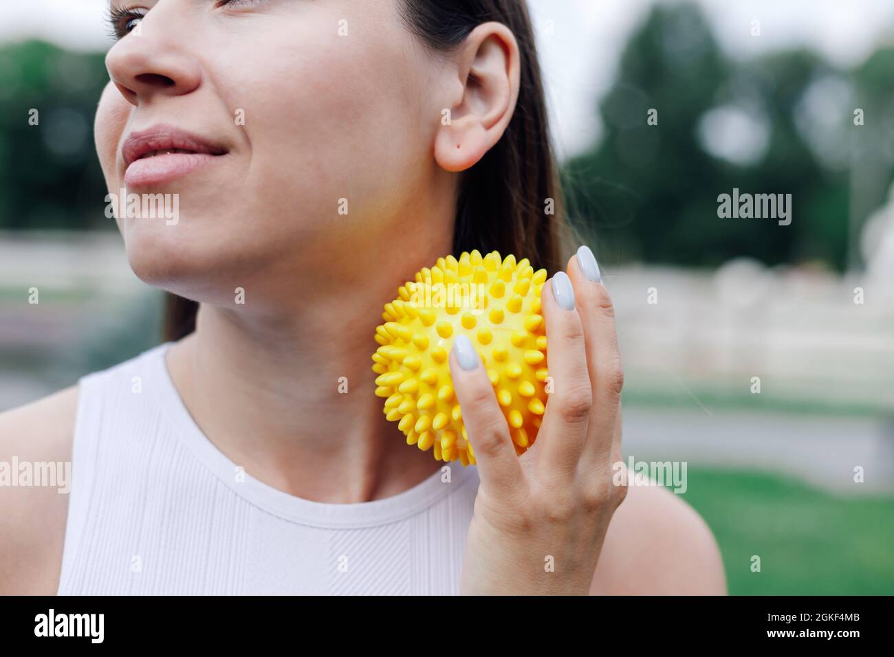 close-up of neck of young woman doing self-massage with spiky rubber ...