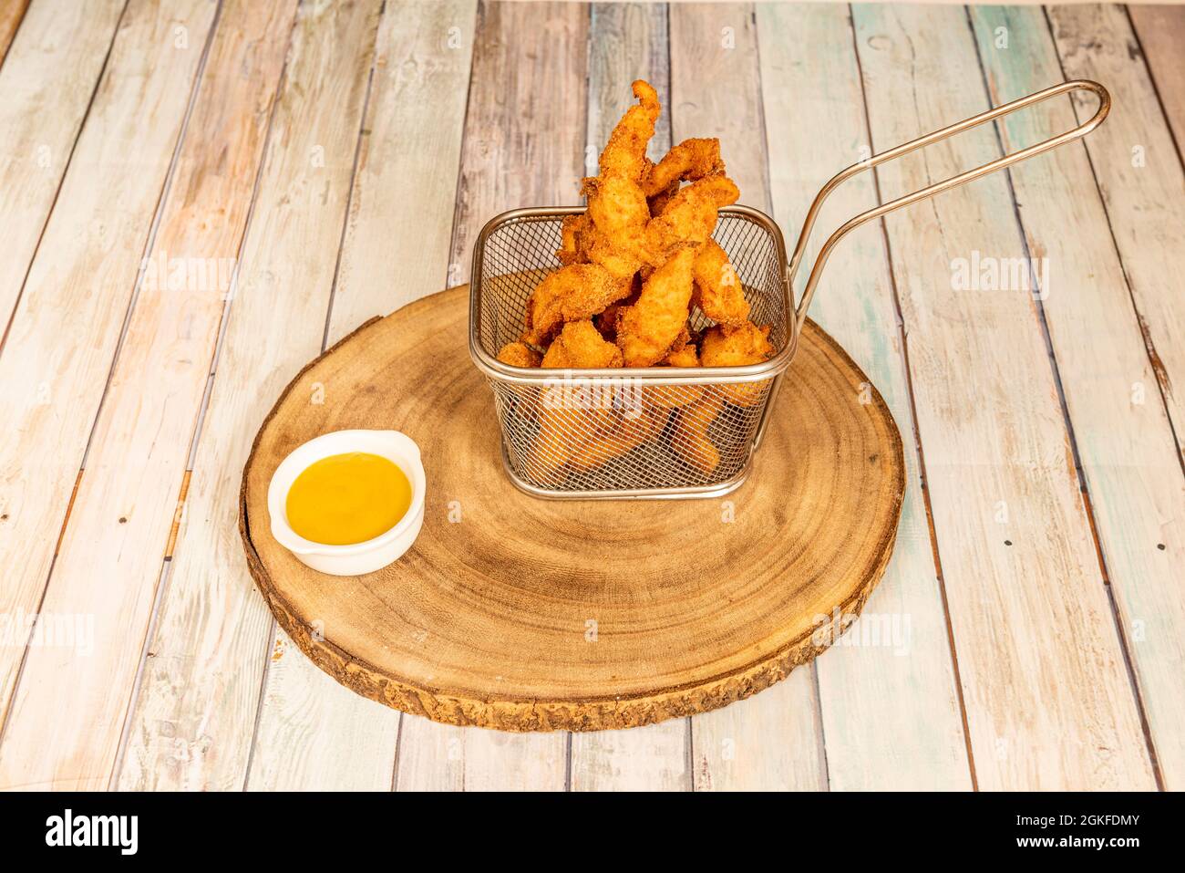 Metal basket for fryer full of chicken fingers with curry sauce on a ...