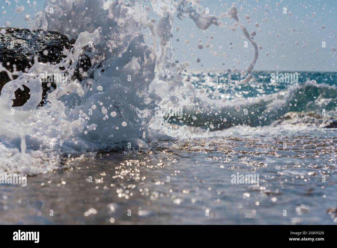 A heavy sea wave breaks into white foam splashes on the shore, big wave ...