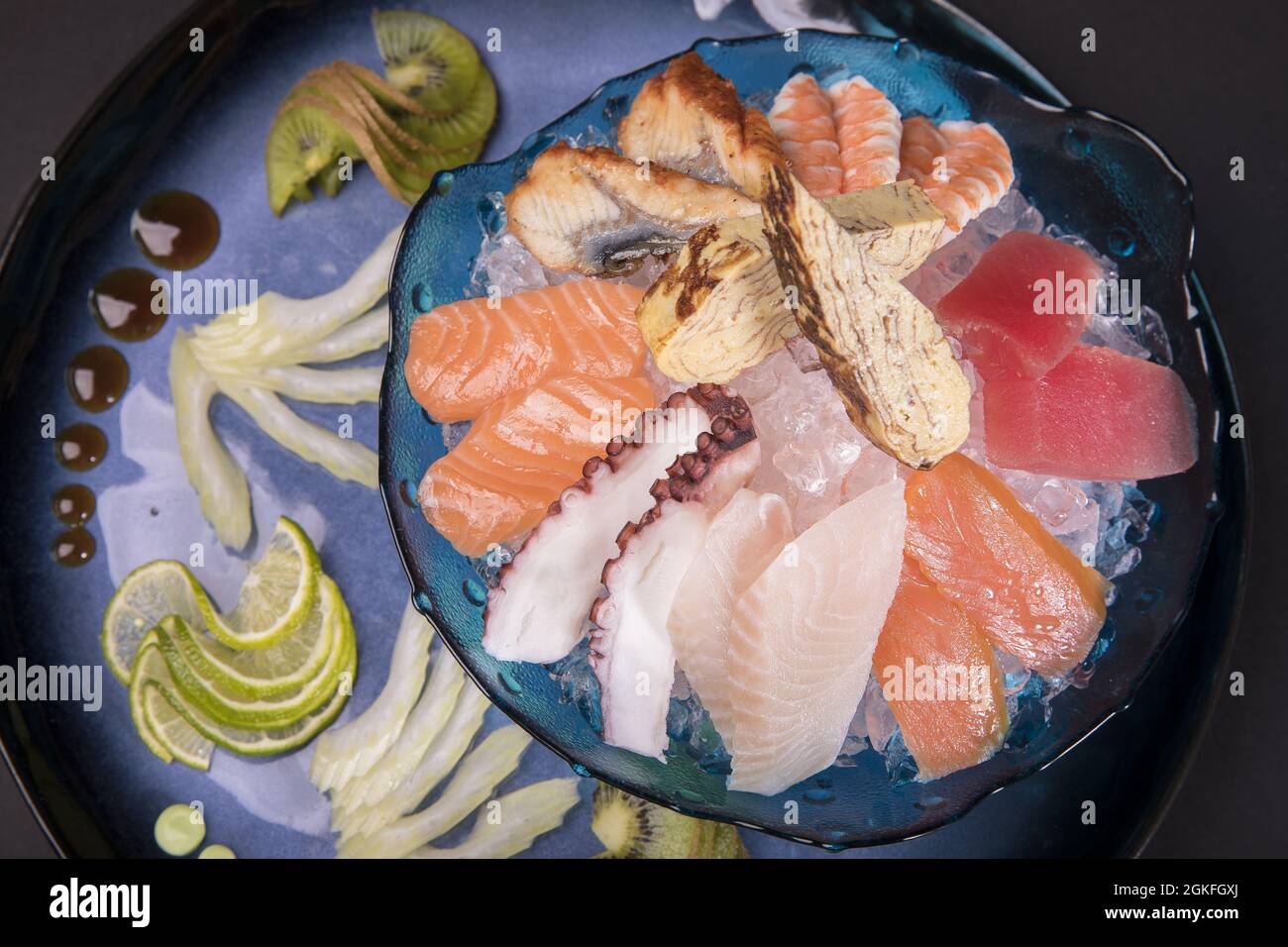 A top view of king prawns, sashimi, and salmon fillet served with kiwi ...