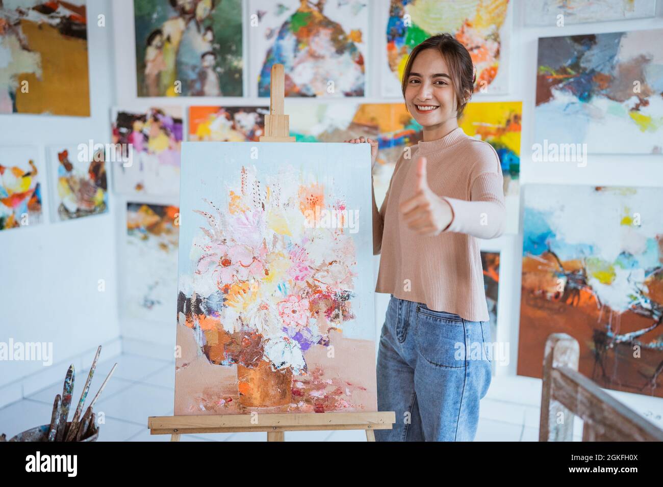 female artist standing next to her painting and showing thumb up Stock ...