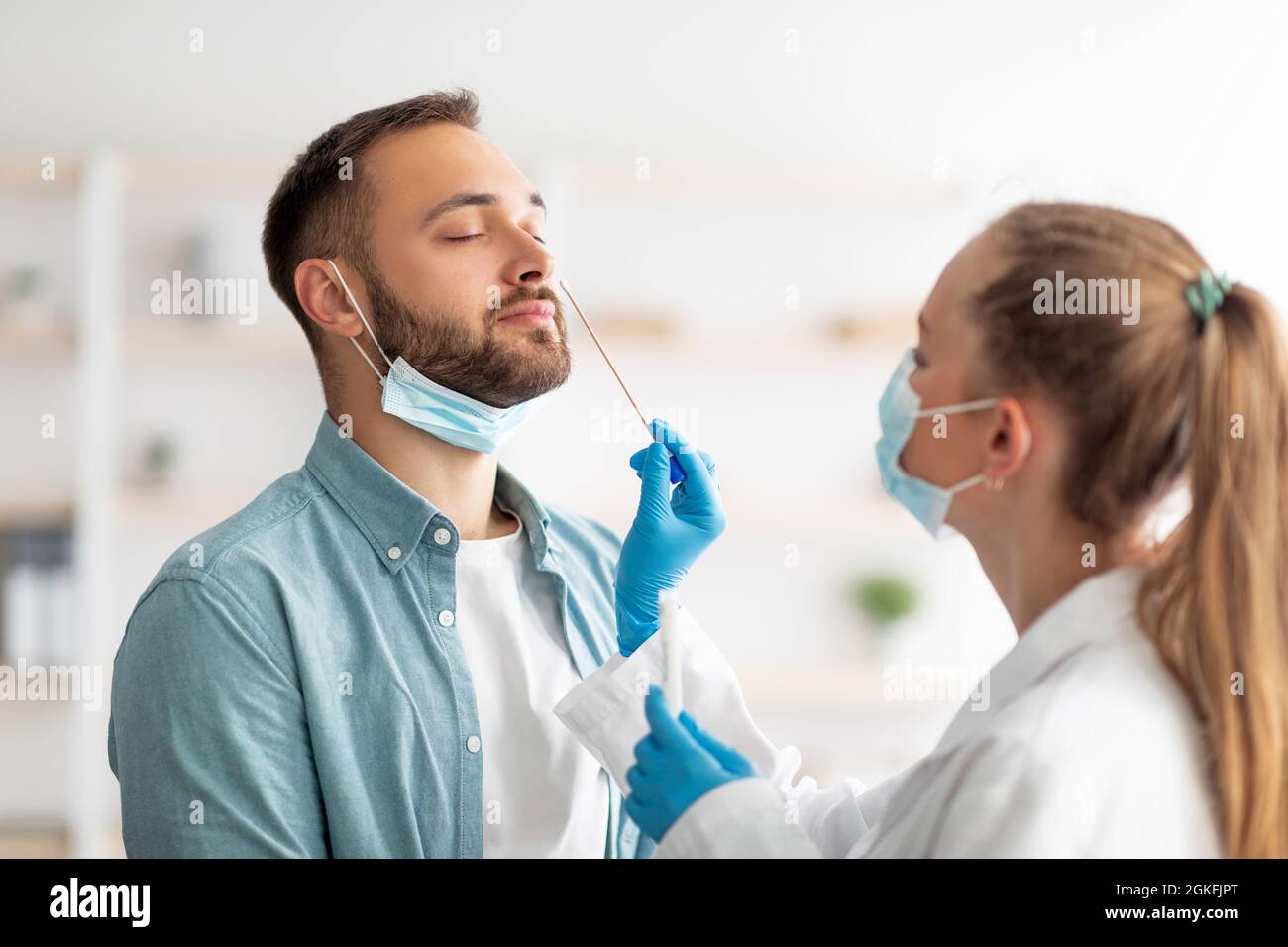 Female doctor making nasal coronavirus PCR test for millennial guy at ...