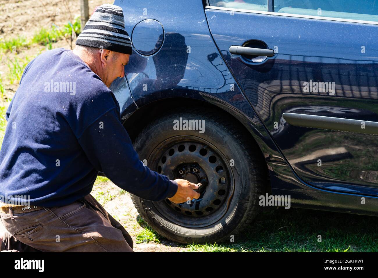 Mechanic changing wheel on car with manual wrench. Mechanic replacing ...
