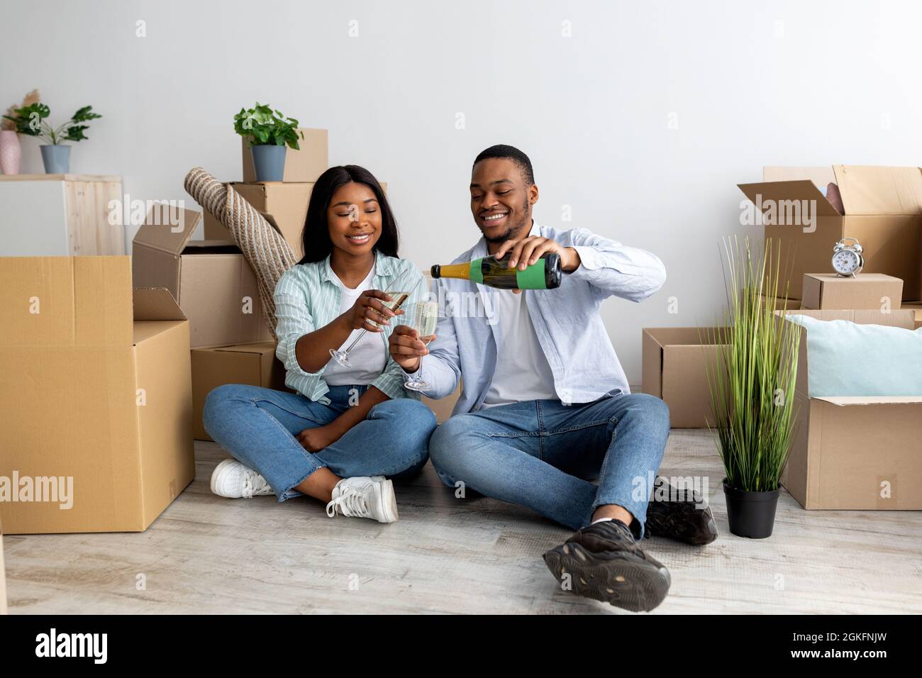 Loving black spouses celebrating moving day with champagne, sitting on ...